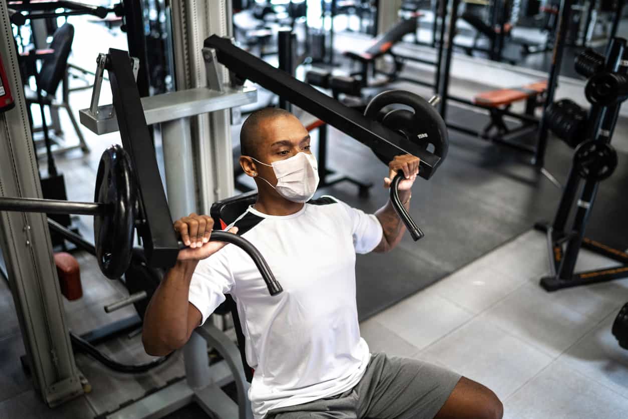 Man doing strength workout exercise in gym with face mask - Hilary ...
